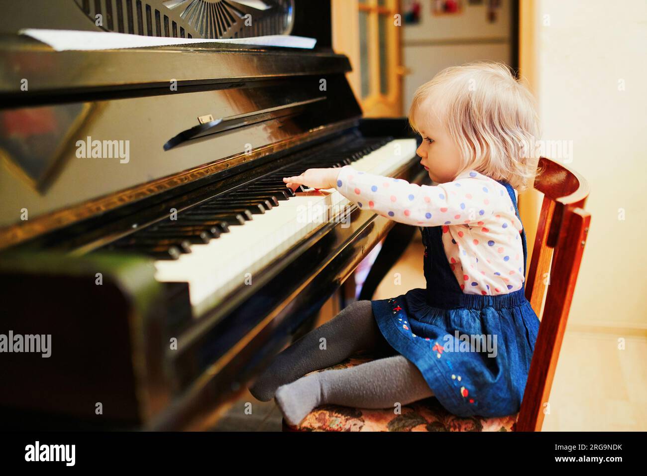 Adorable little girl playing piano. Toddler having fun while learning ...