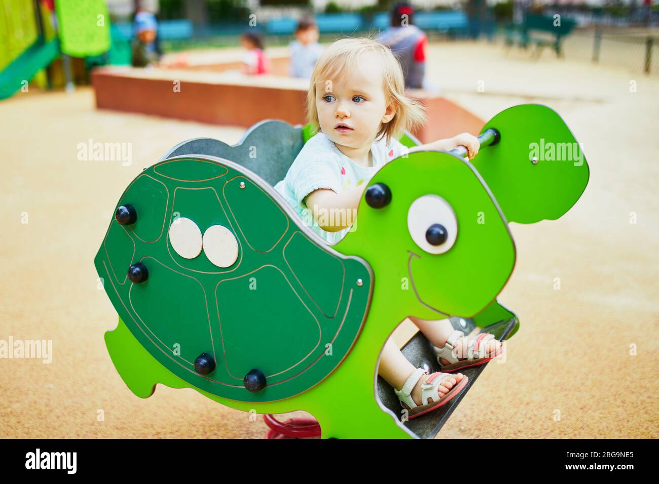 Adorable toddler girl having fun on playground, using spring rider ...