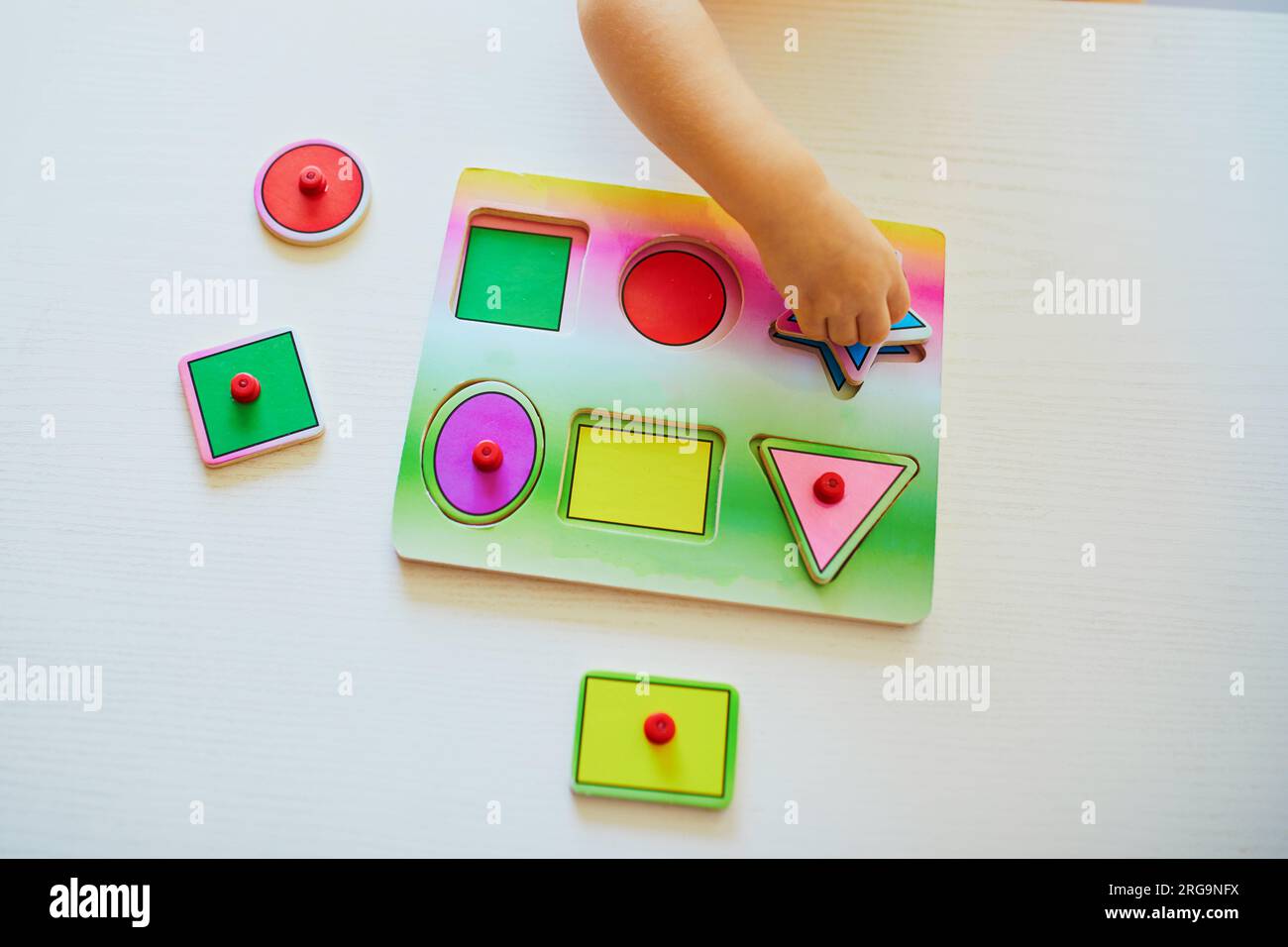 Toddler girl or boy doing wooden puzzle. Child learning geometric ...