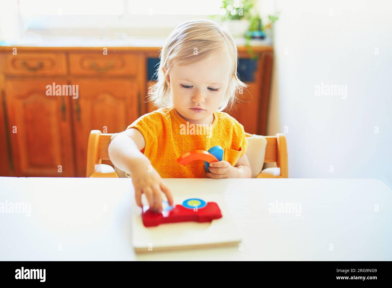 Adorable toddler girl doing wooden puzzle. Child learning geometric ...