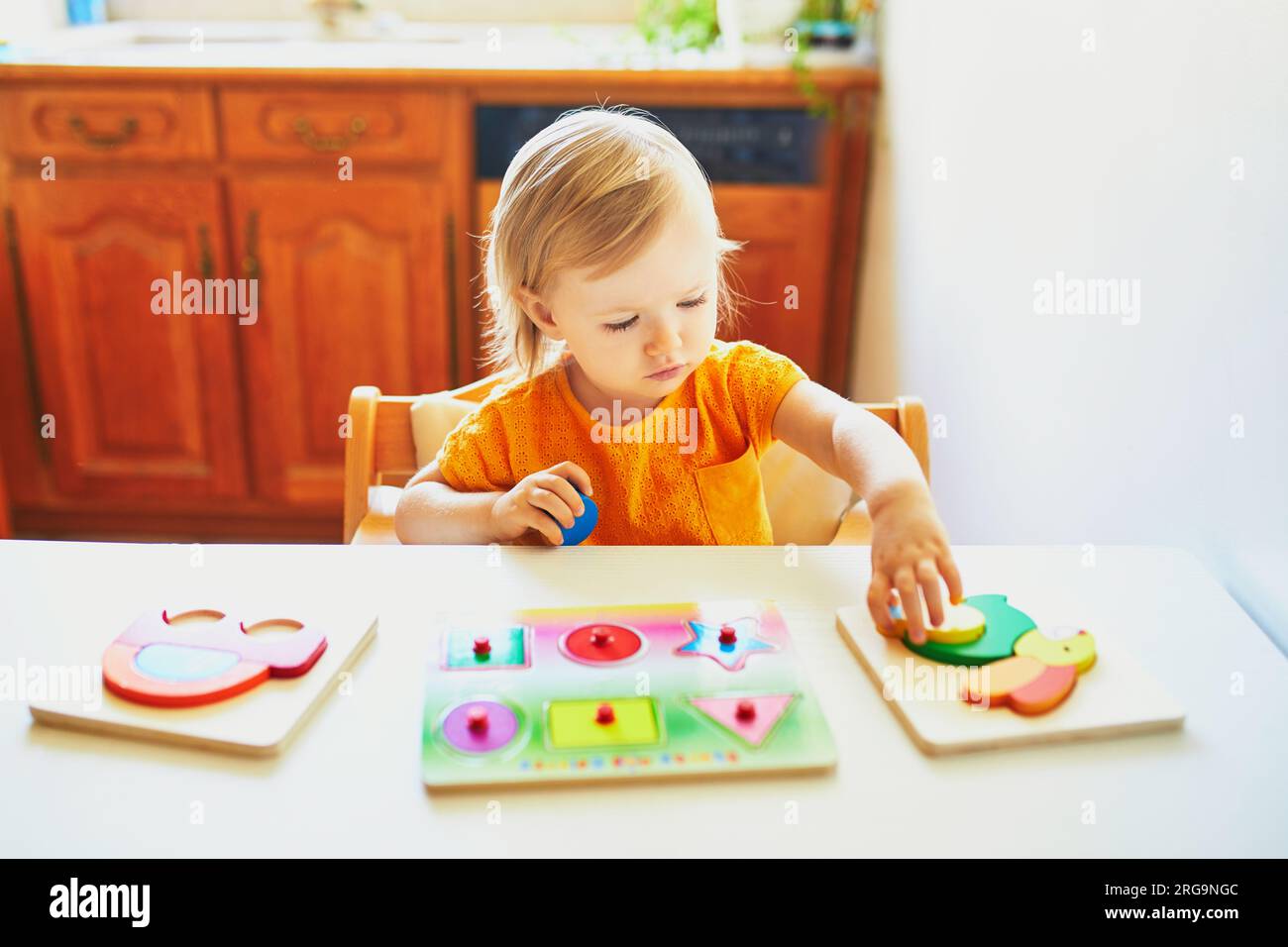 Adorable toddler girl doing wooden puzzle. Child learning geometric ...