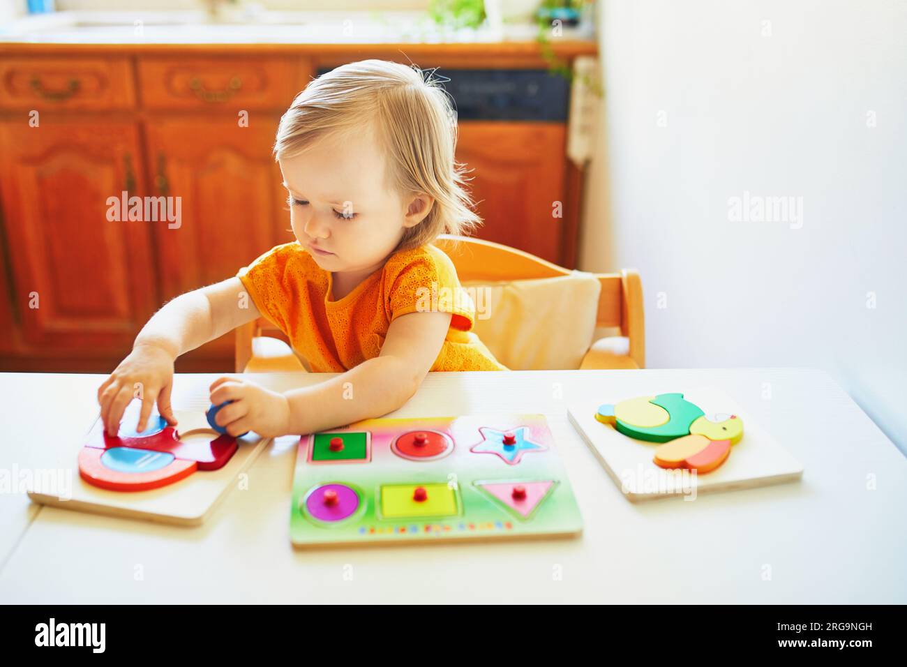Adorable toddler girl doing wooden puzzle. Child learning geometric ...