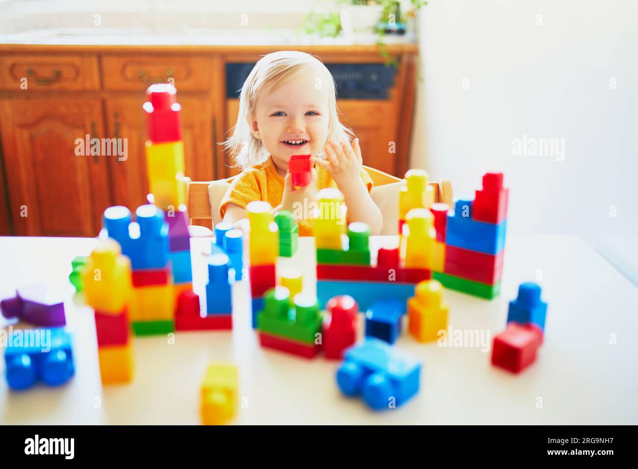 Adorable little girl playing with colorful plastic construction blocks ...