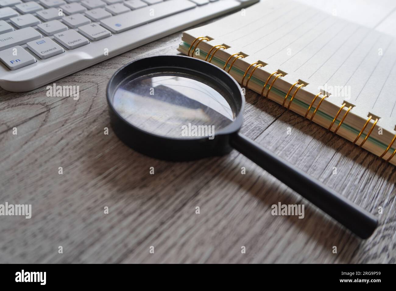 Close up image of magnifying glass, notebook and computer keyboard on ...