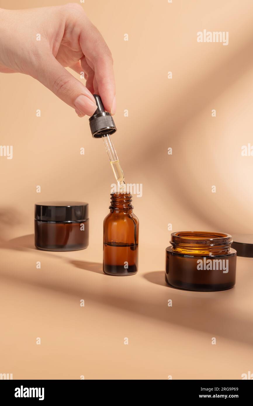 Hand, product and serum with a woman on a beige background to promote ...