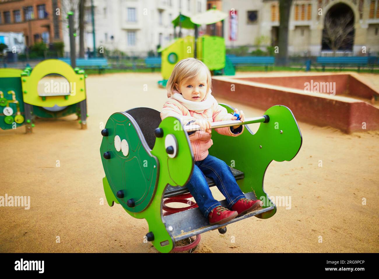 Adorable toddler girl having fun on spring rider on playground. Outdoor ...