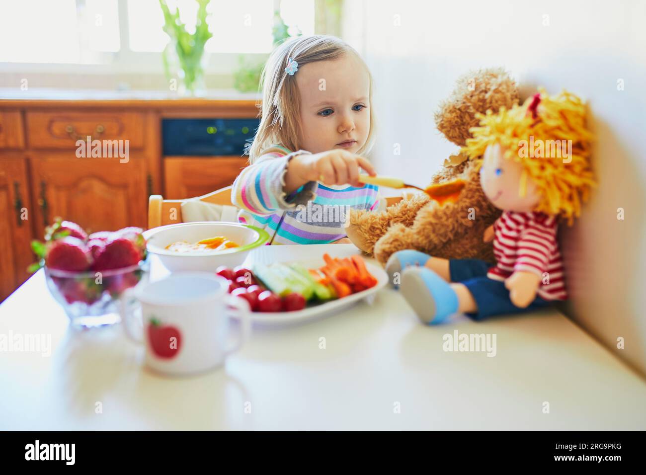 Adorable toddler girl eating fresh fruits and vegetables for lunch ...