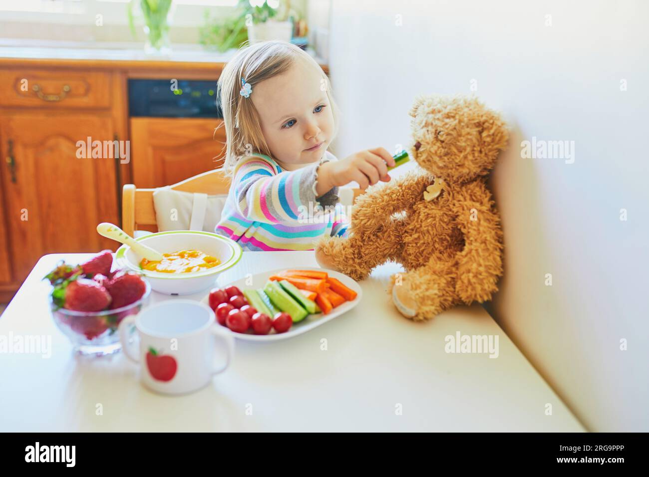 Adorable toddler girl eating fresh fruits and vegetables for lunch ...