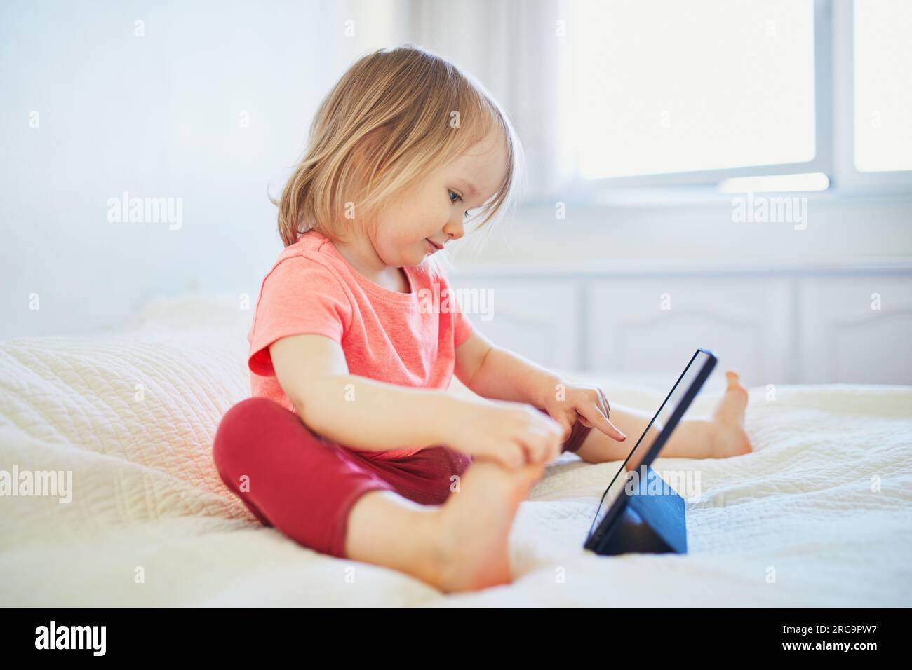 Toddler girl with digital tablet at home. Child watching cartoons. Kid ...