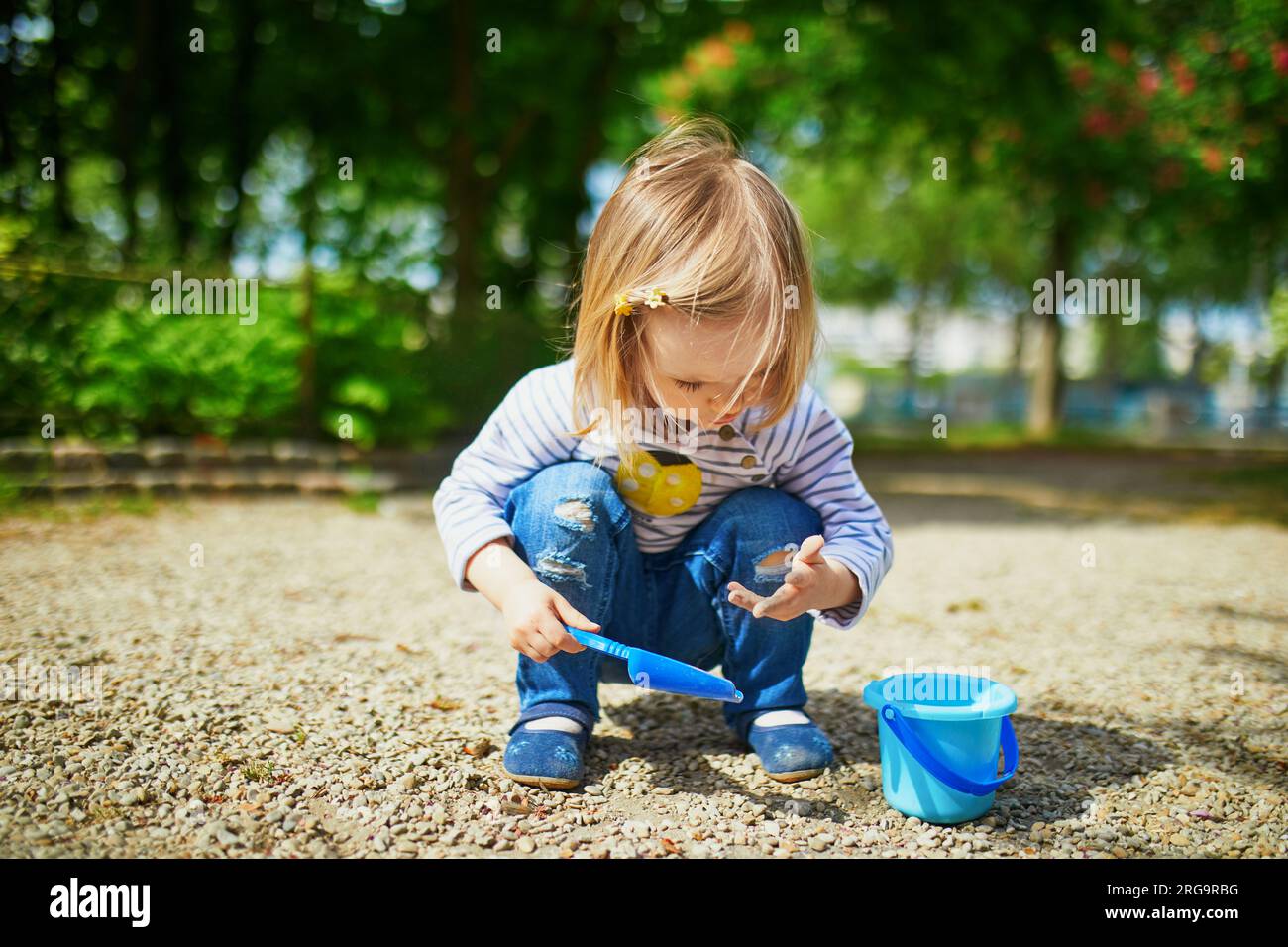 Adorable toddler girl playing with bucket and shovel, making mudpies ...