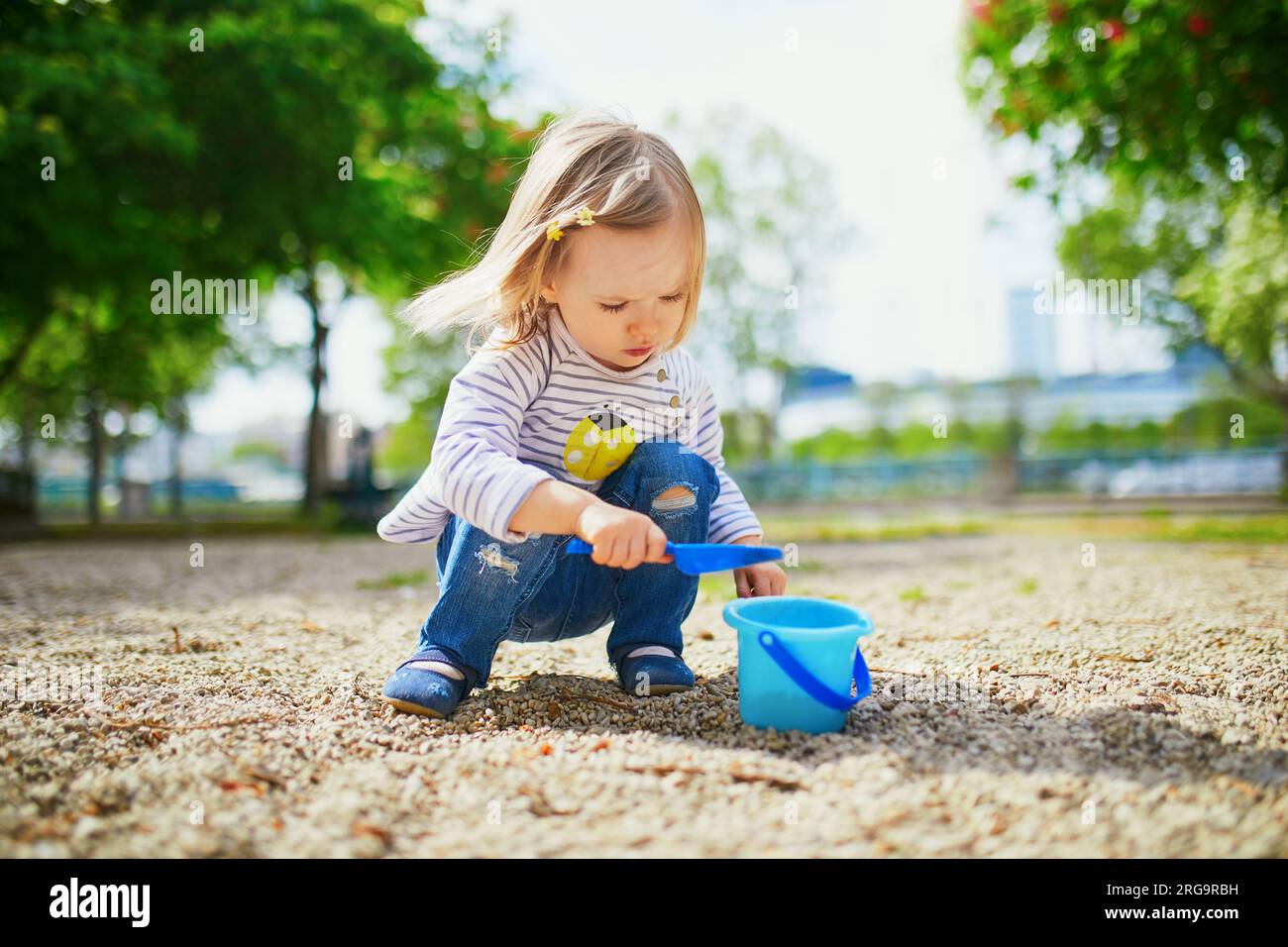 Adorable toddler girl playing with bucket and shovel, making mudpies ...