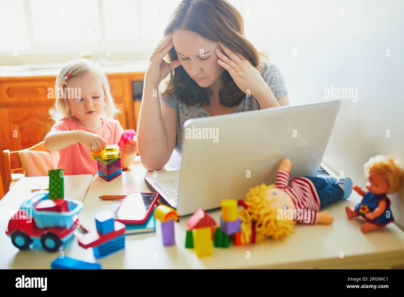 Exhausted and stressed mother working from home with toddler ...