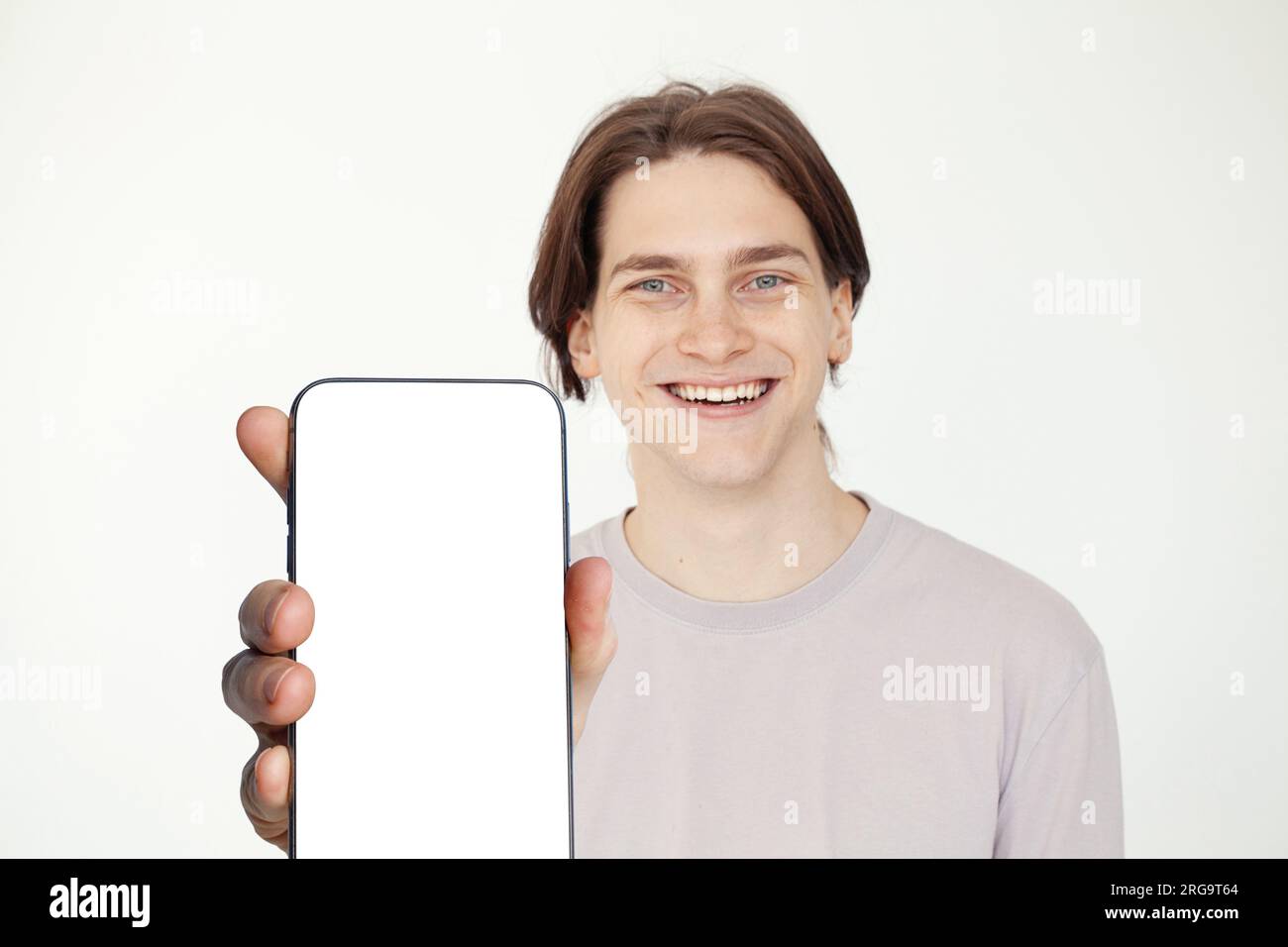 Cheerful emotional man holding big blank cell phone in his hand showing ...