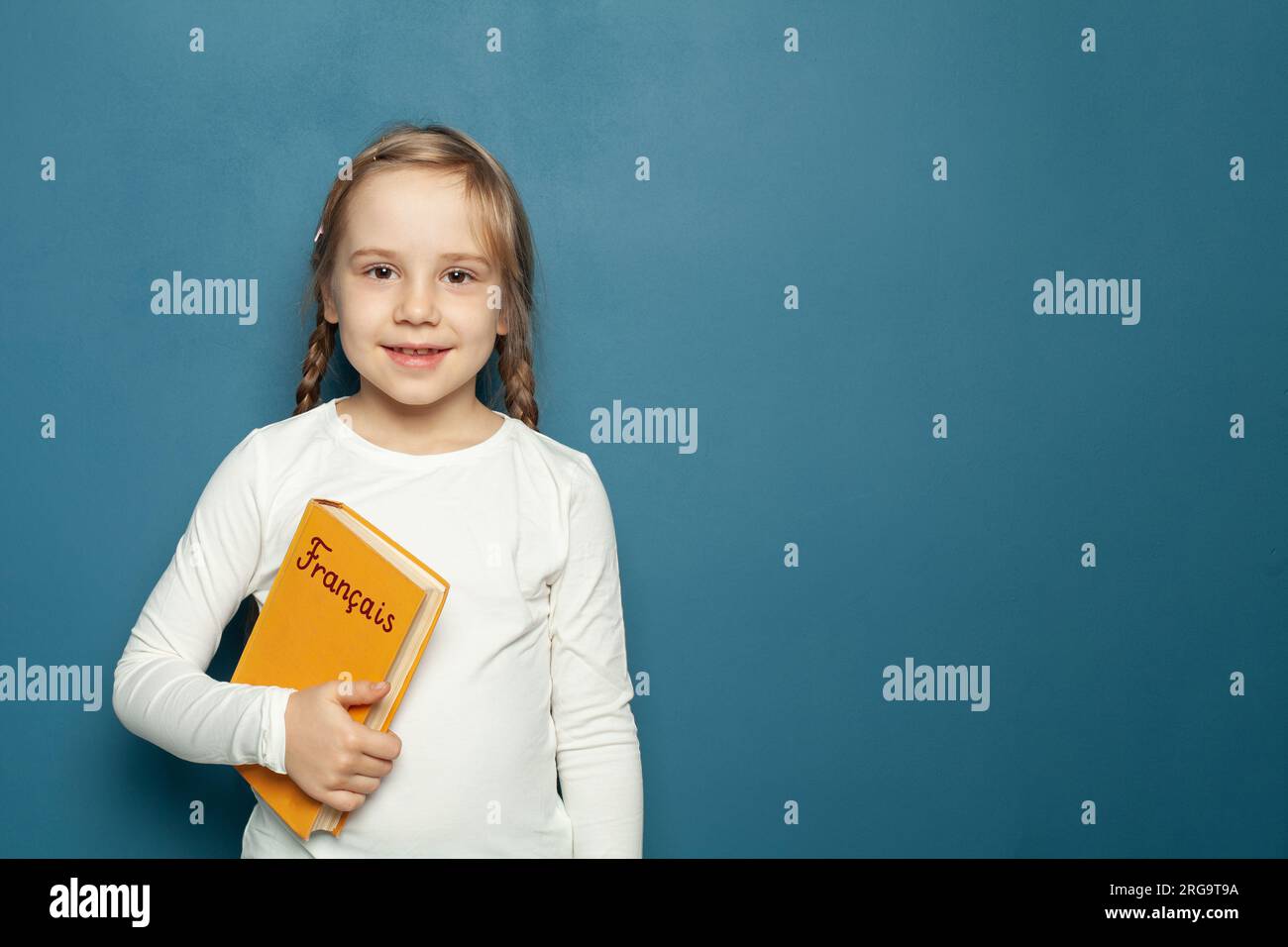 Child student girl with French language book on the background of blue ...