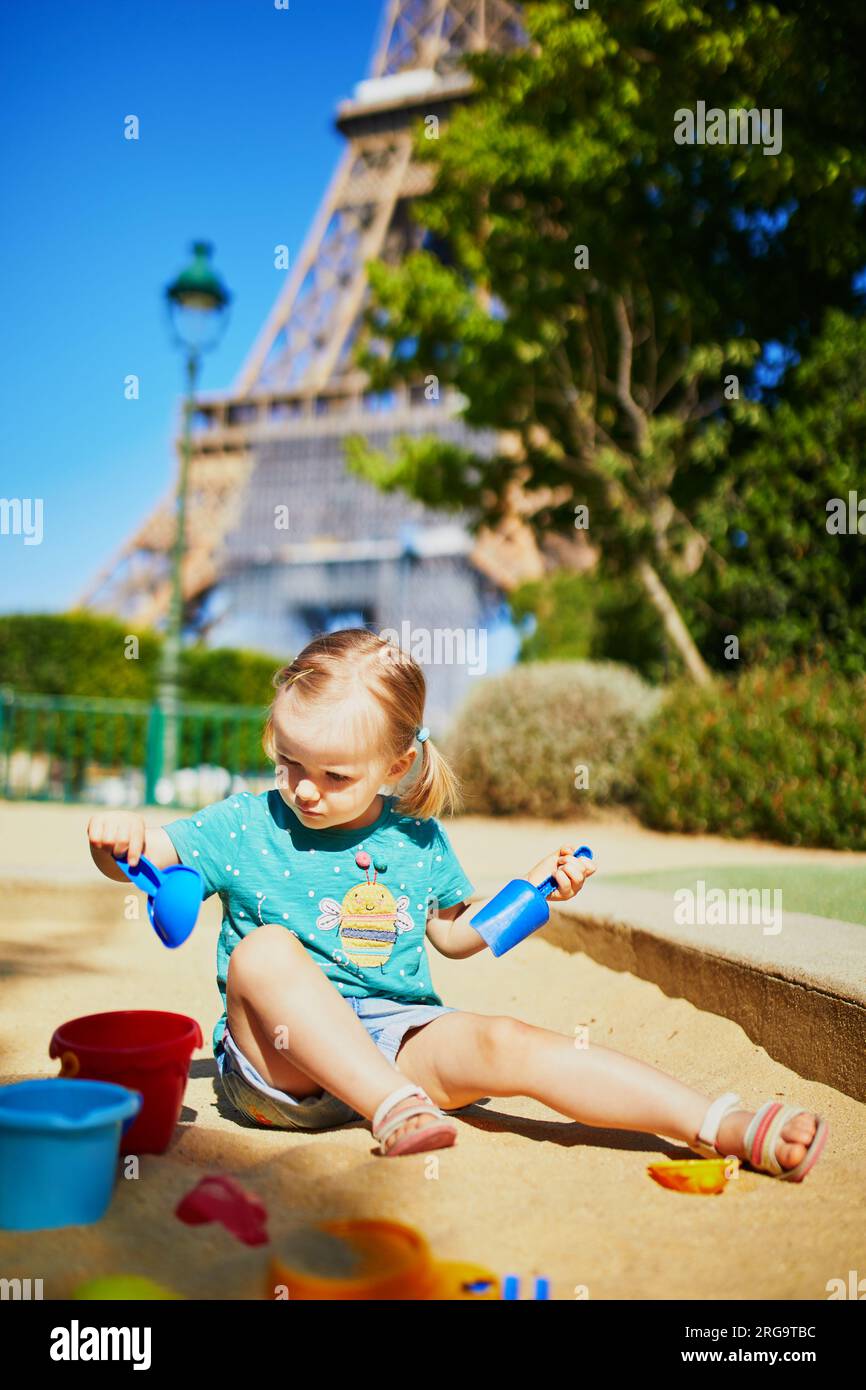 Adorable little girl having fun on playground in sandpit near the ...