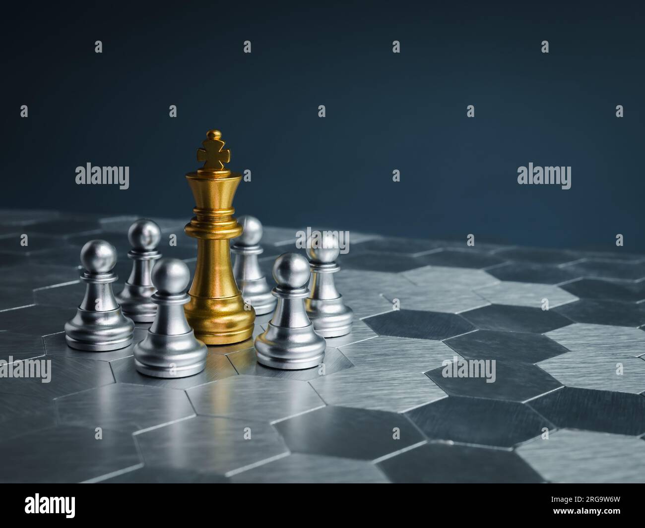 Golden king chess piece standing in the center of little silver pawn ...