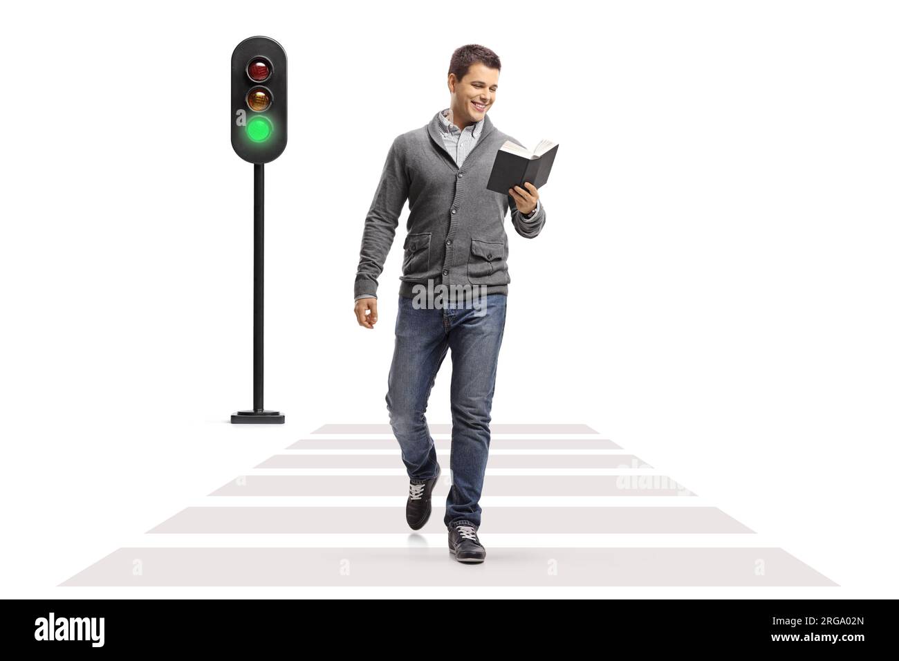 Full length portrait of a young man reading a book and walking across a ...