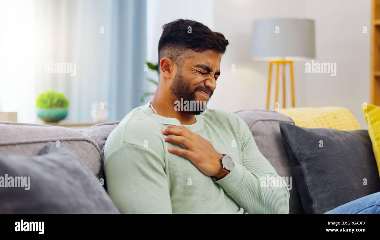 Man, sofa and chest pain in home, massage and relief from stress or ...