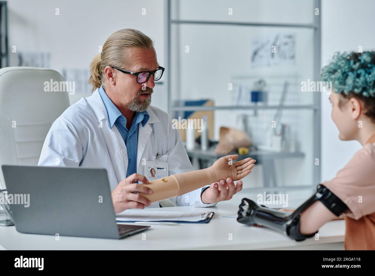 Portrait of senior prosthetist consulting young woman with disability ...