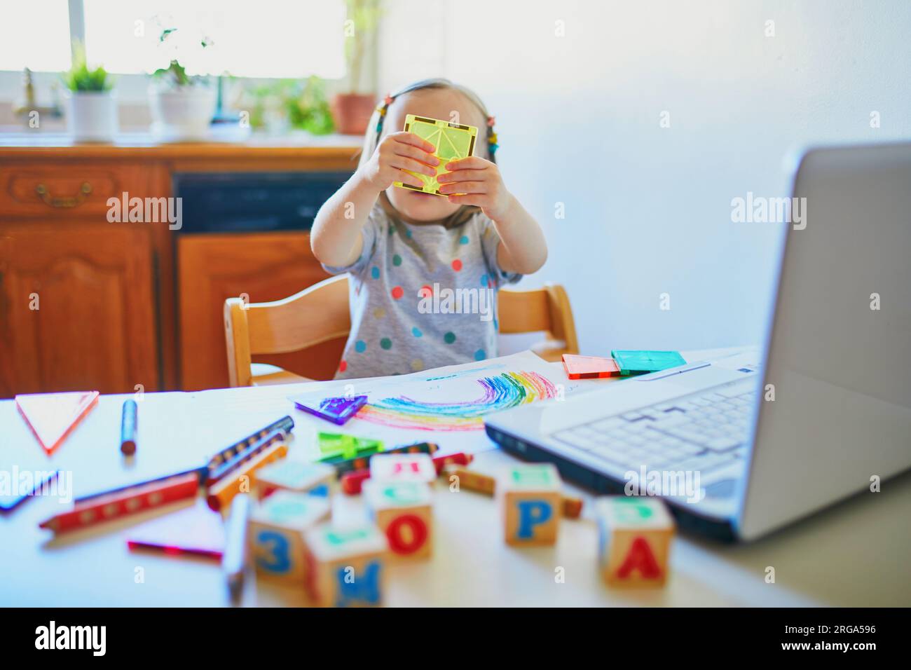 Toddler girl learning shapes in front of laptop. Kid using computer to ...