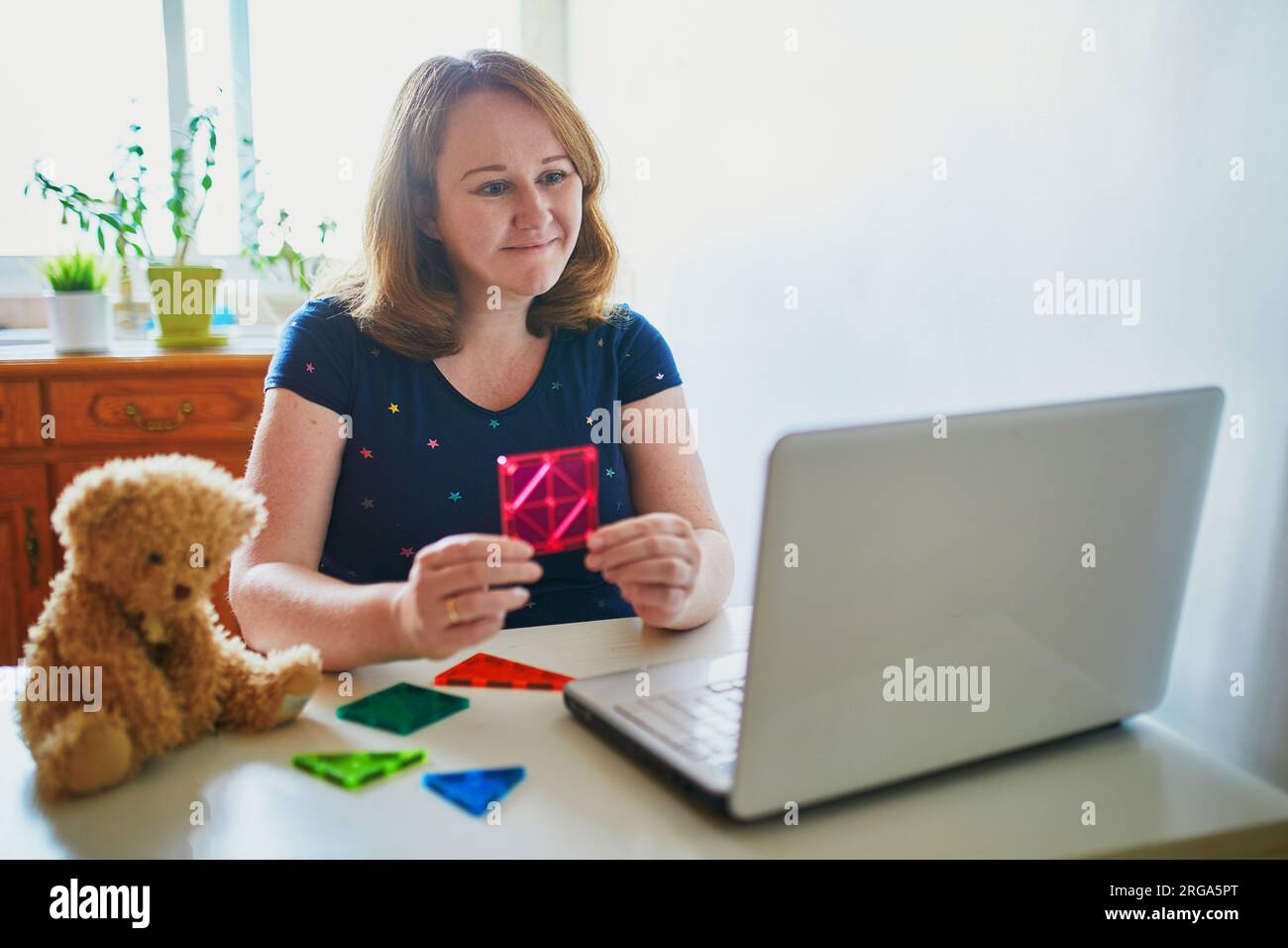 Kindergarten teacher in front of laptop having video conference chat ...