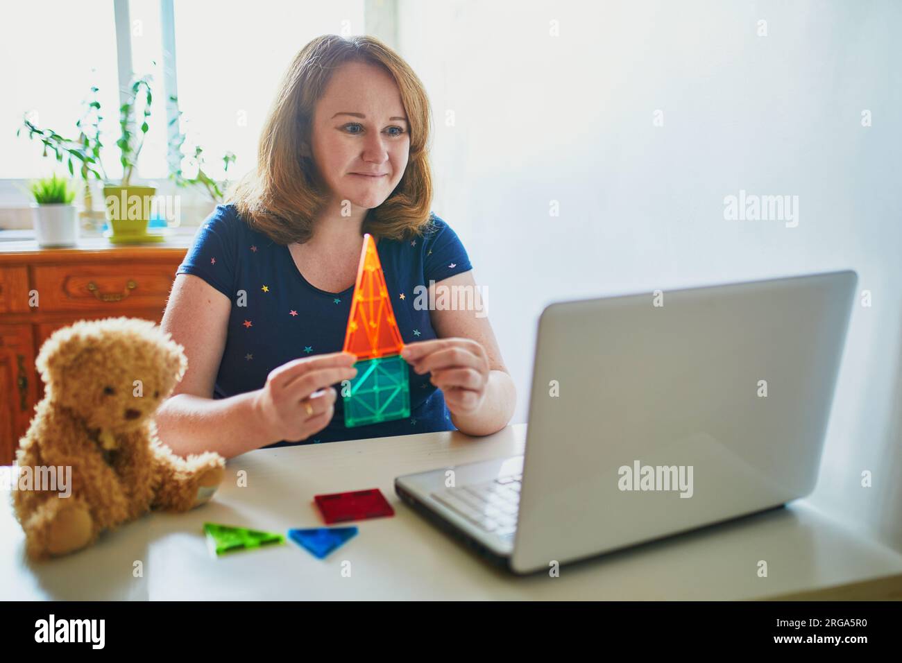 Kindergarten teacher in front of laptop having video conference chat ...