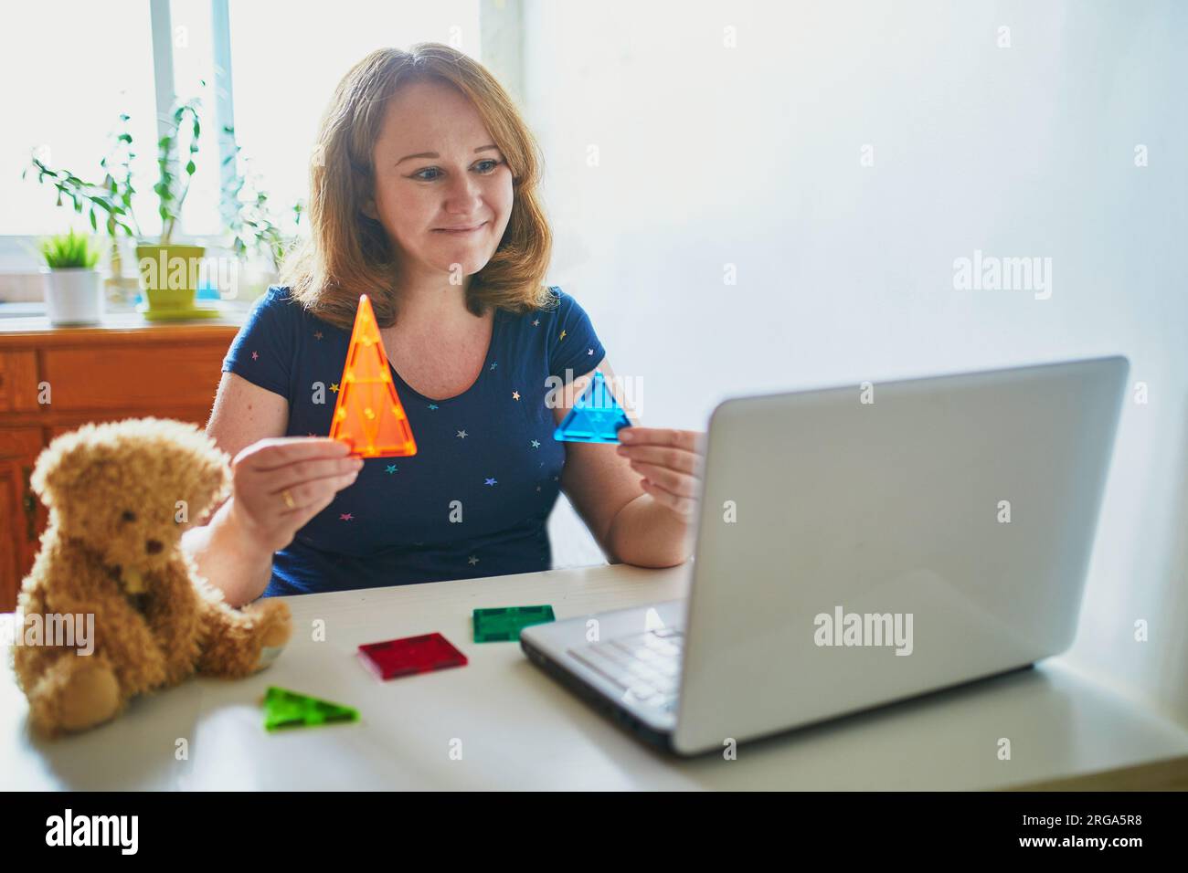 Kindergarten teacher in front of laptop having video conference chat ...