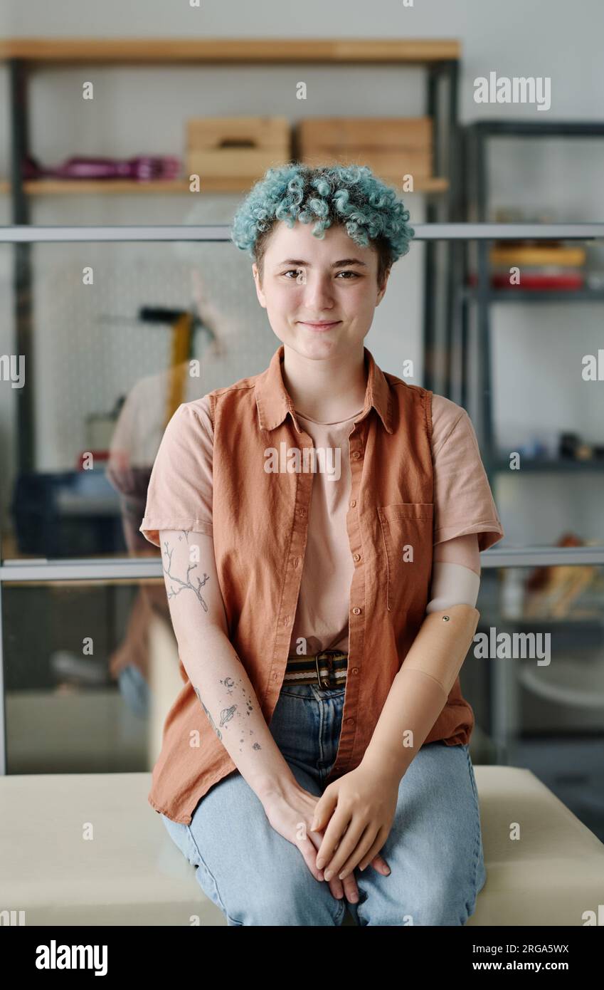 Vertical portrait of teenage girl with prosthetic arm posing in doctors ...
