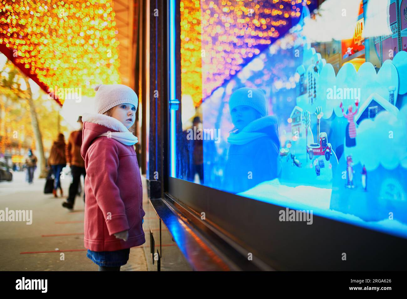 Toddler girl looking at window glass of large department store ...