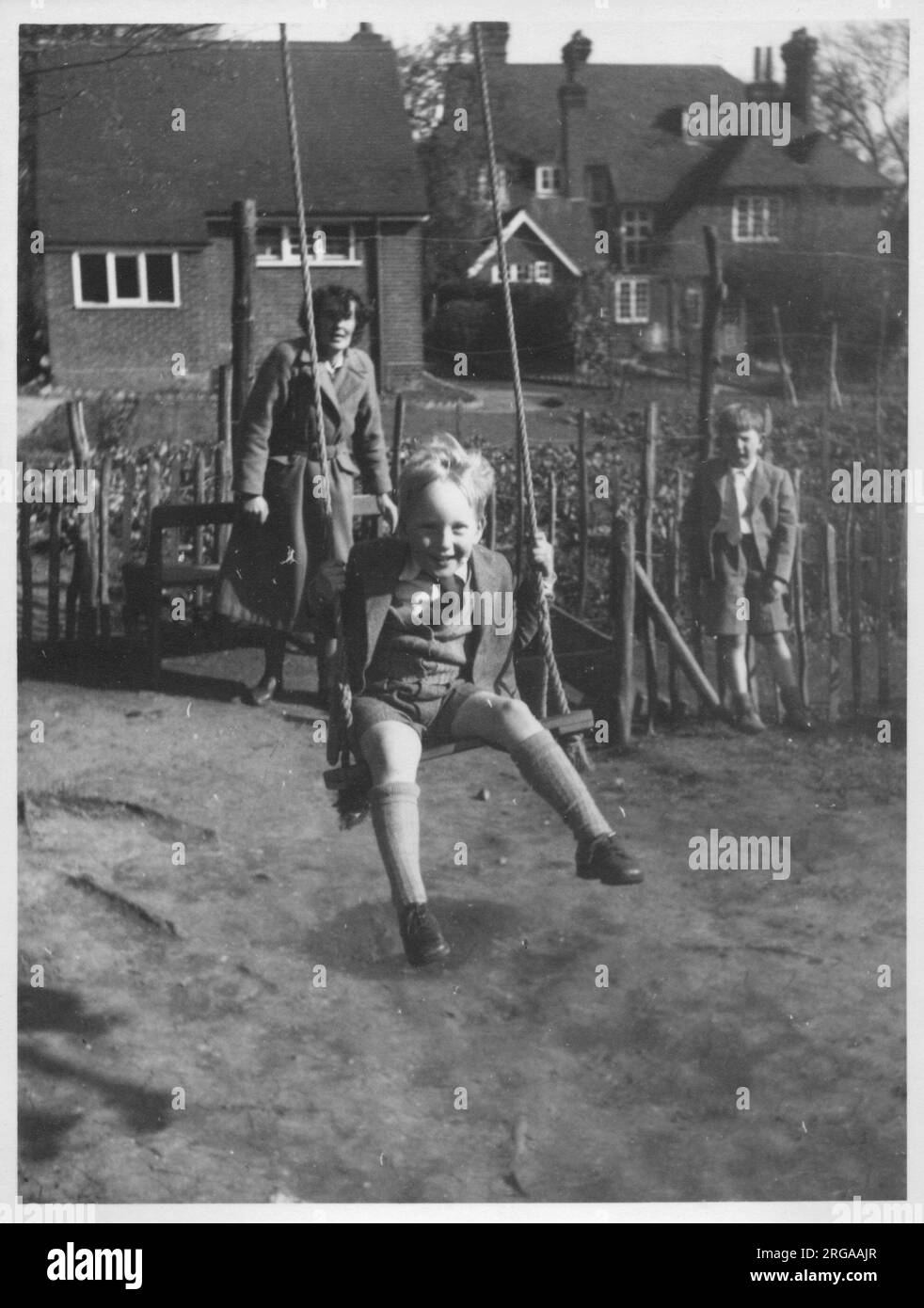 A little boy beaming widely as he gets a push on a garden swing ...