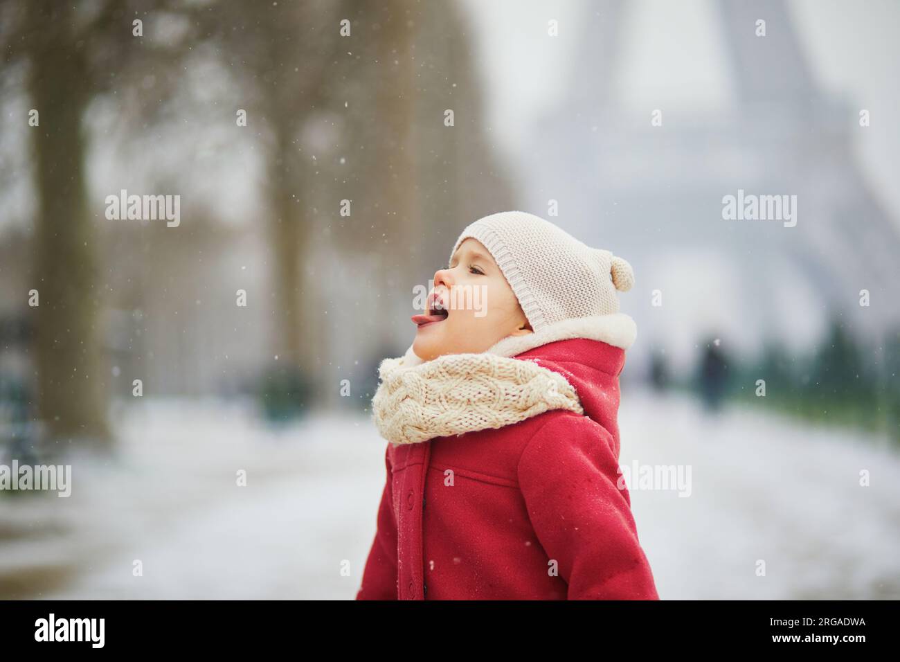Adorable toddler girl catching snowflakes with her tongue near the ...