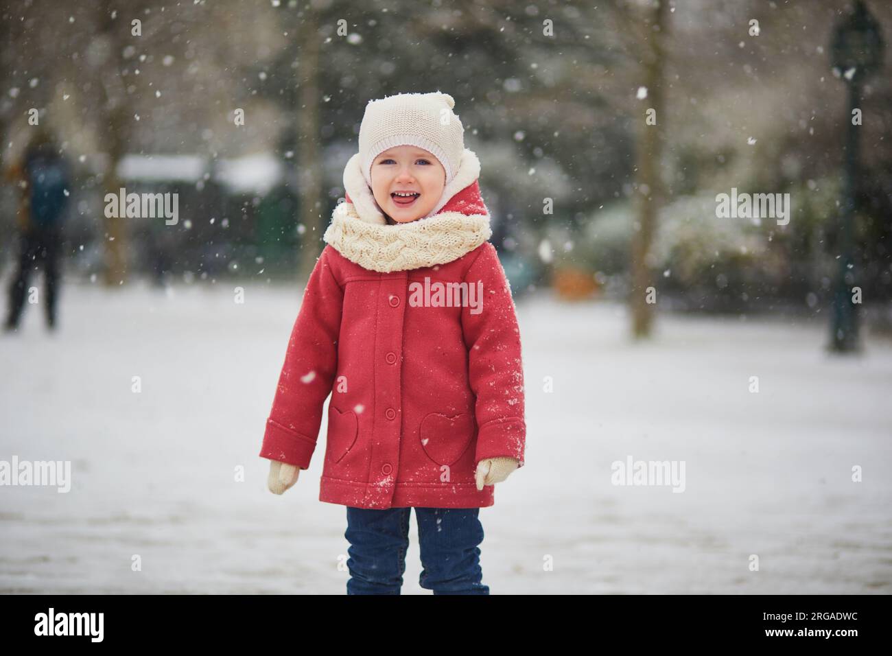 Adorable toddler girl on a day with heavy snowfall. Happy child playing ...