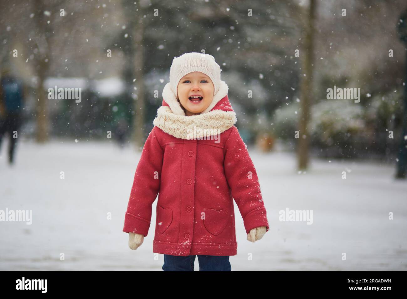 Adorable toddler girl on a day with heavy snowfall. Happy child playing ...