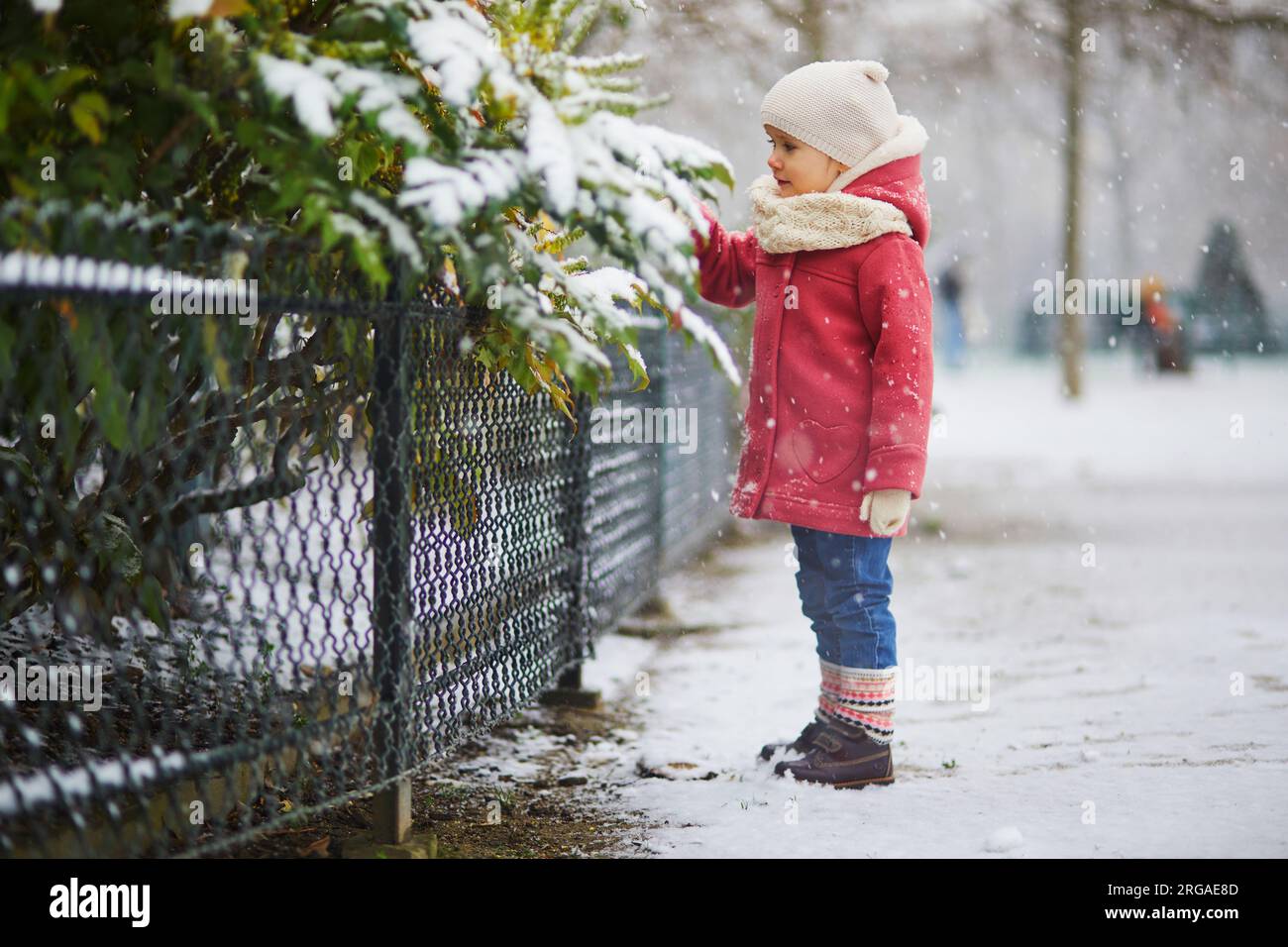 Adorable toddler girl on a day with heavy snowfall. Happy child playing ...