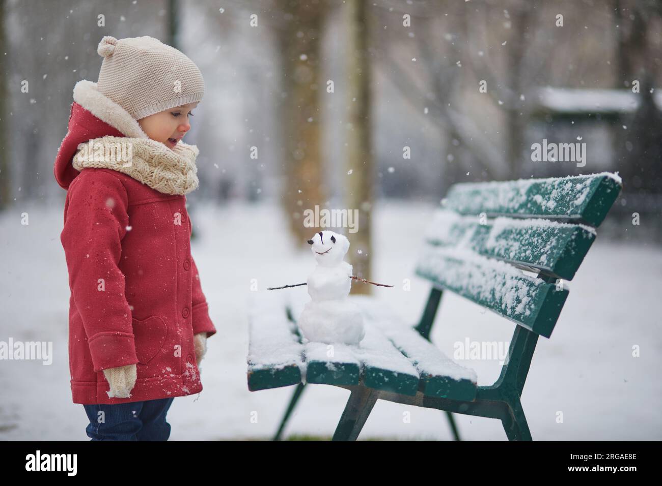 Adorable toddler girl building a snowman on a day with heavy snowfall ...