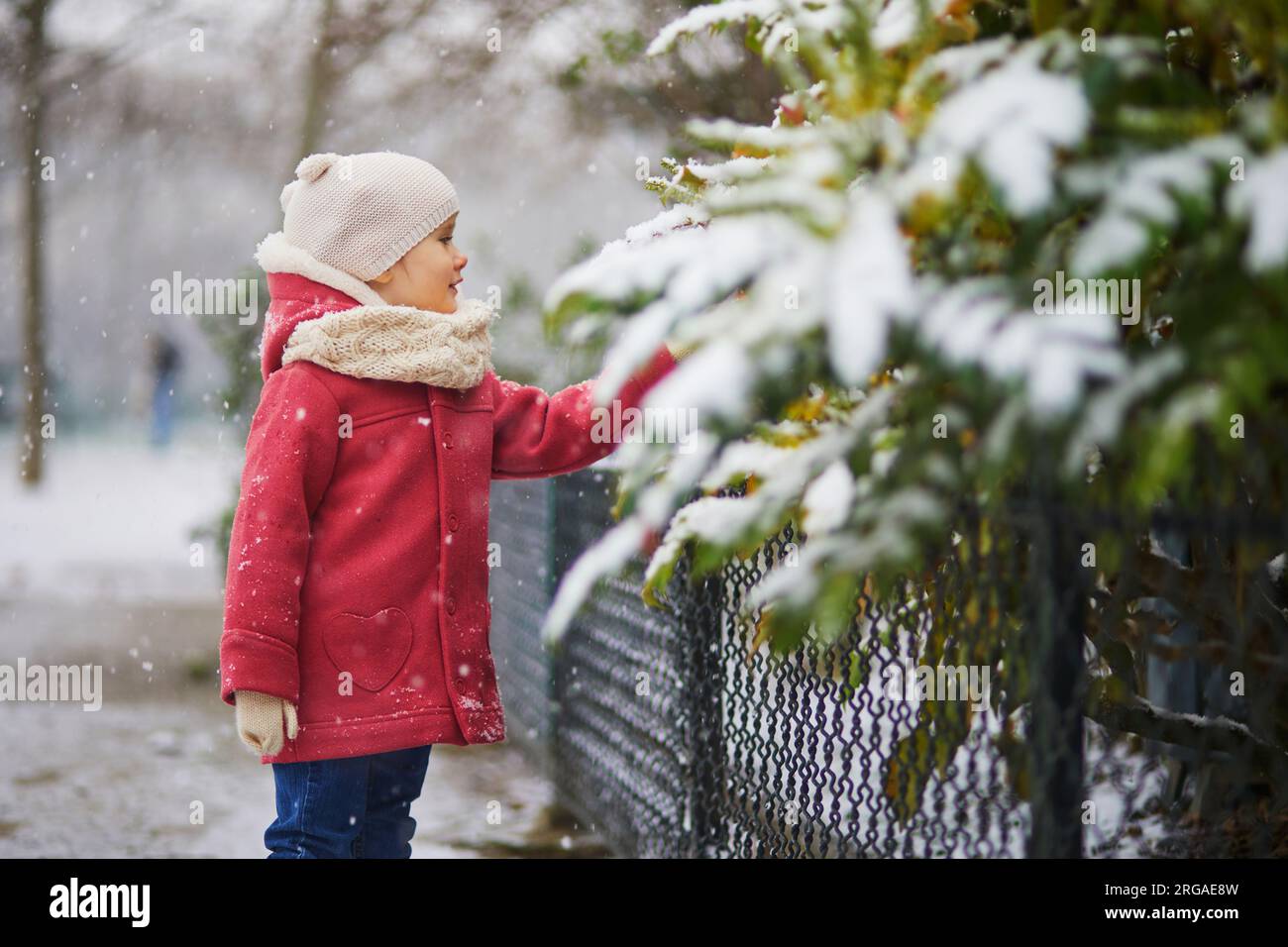 Adorable toddler girl on a day with heavy snowfall. Happy child playing ...