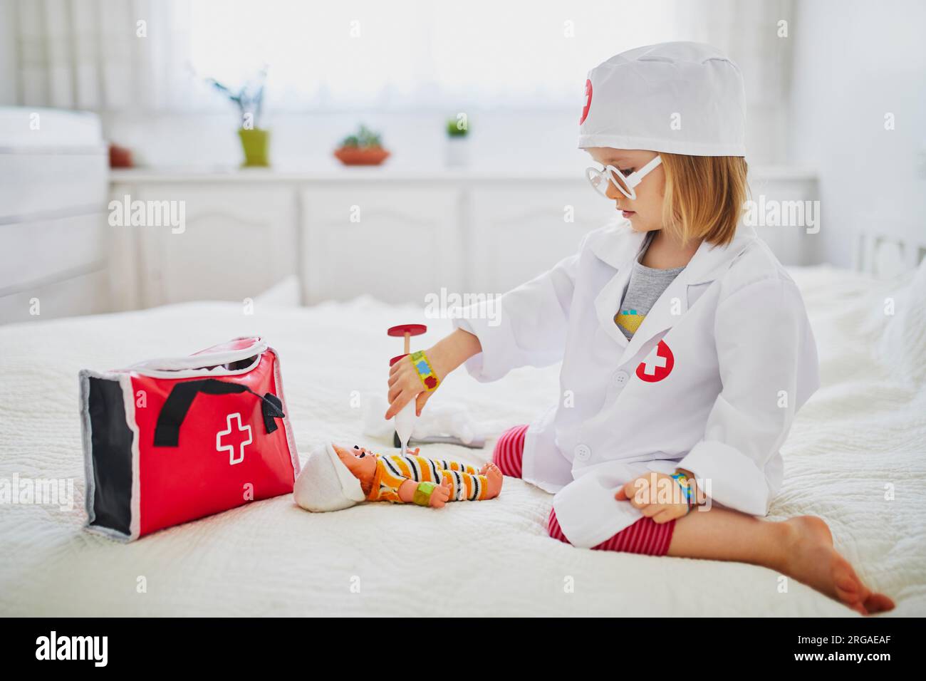 Adorable toddler girl in white coat with syringe playing doctor and ...