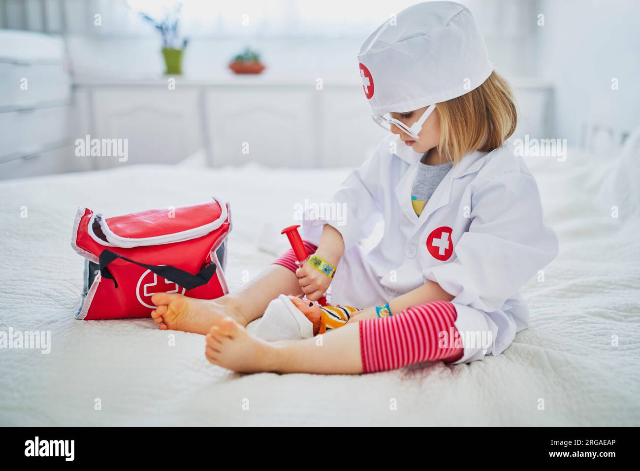 Adorable toddler girl in white coat with syringe playing doctor and ...