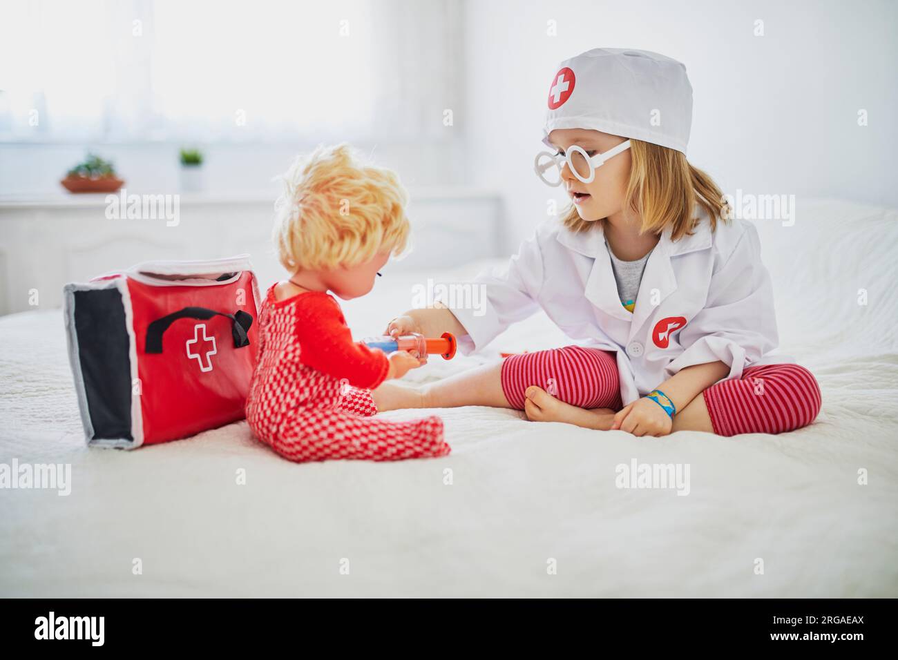 Adorable toddler girl in white coat with syringe playing doctor and ...