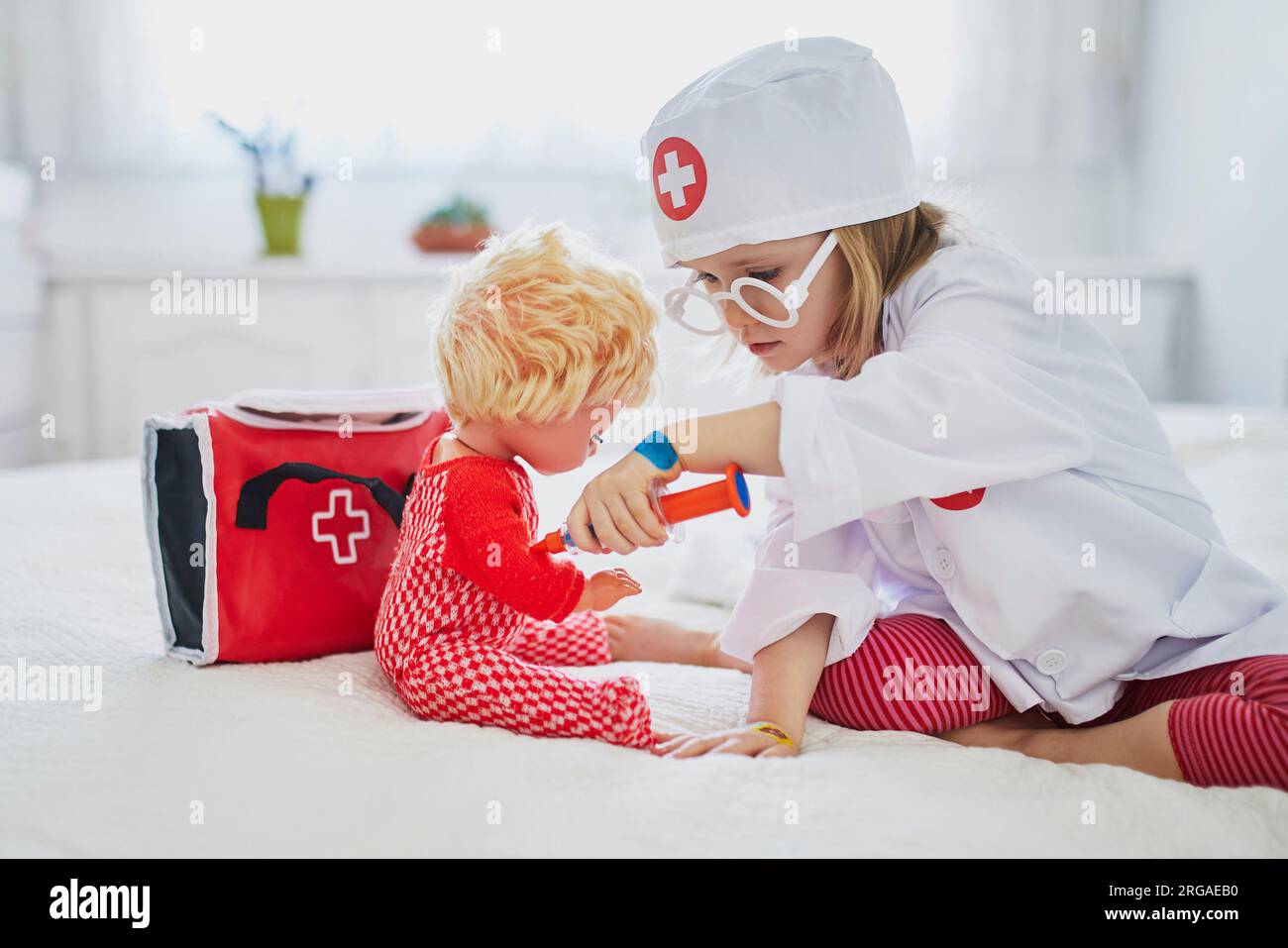 Adorable toddler girl in white coat with syringe playing doctor and ...