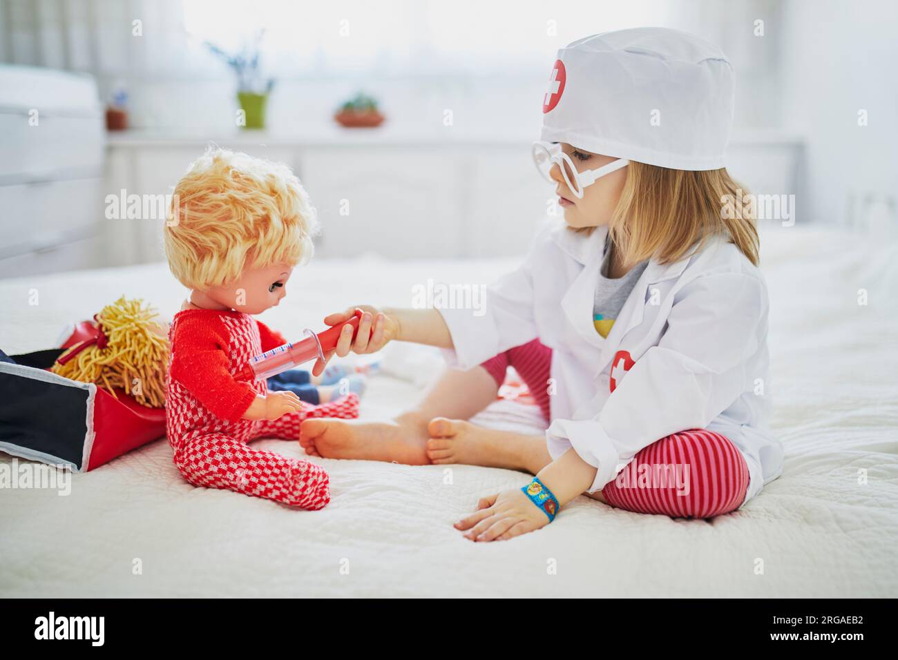Adorable toddler girl in white coat with syringe playing doctor and ...