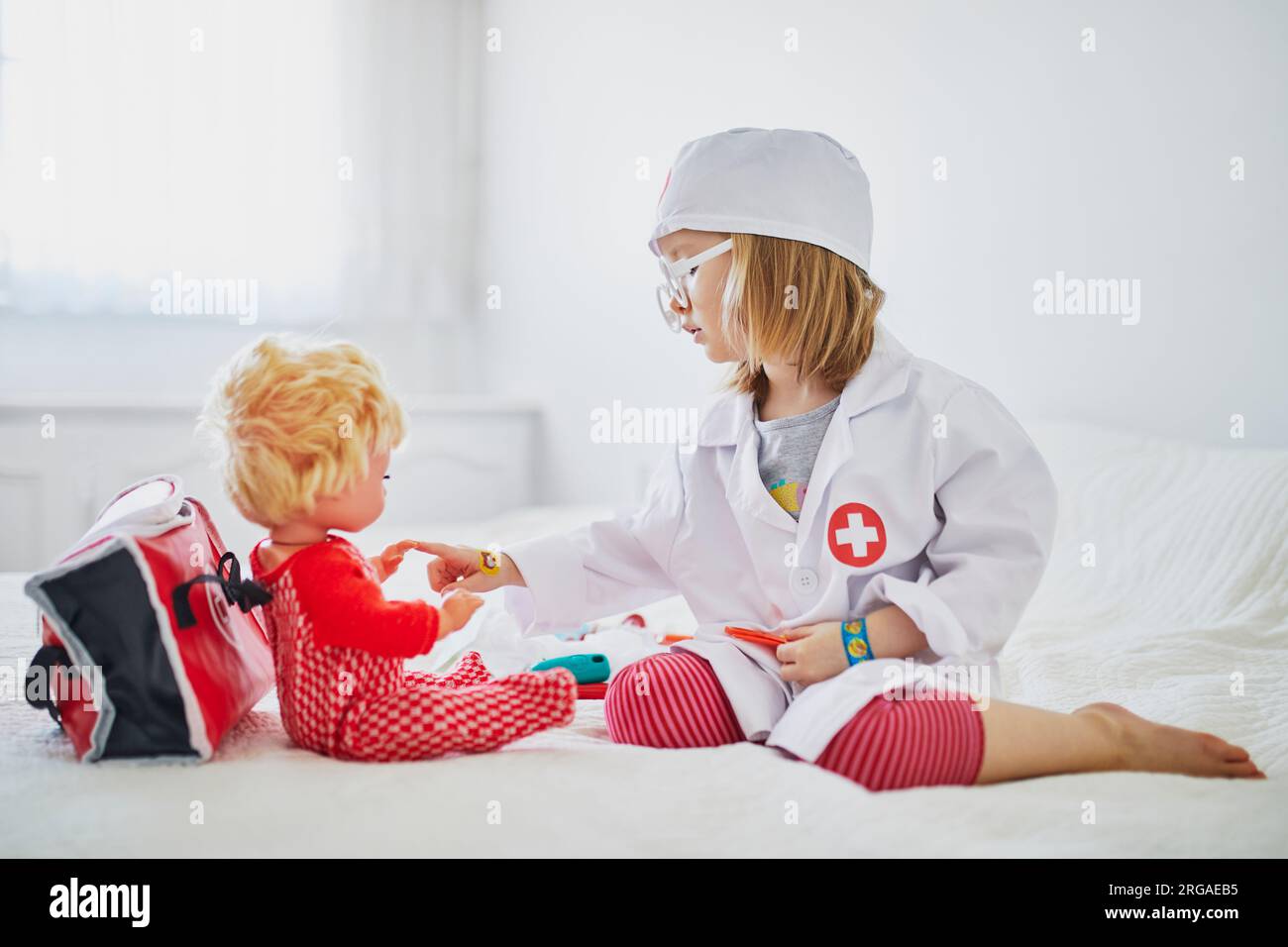 Adorable toddler girl in white coat with syringe playing doctor and ...
