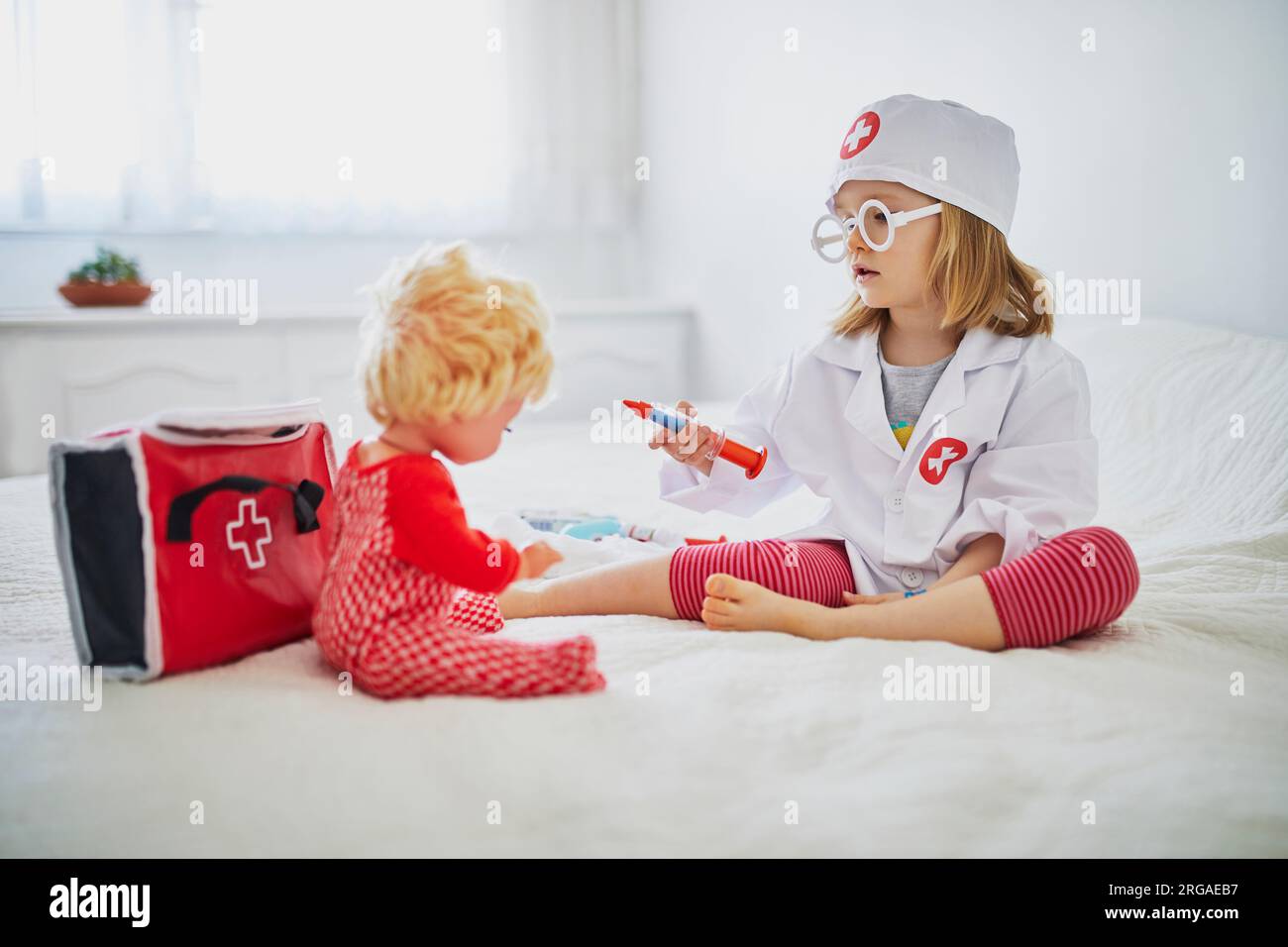 Adorable toddler girl in white coat with syringe playing doctor and ...