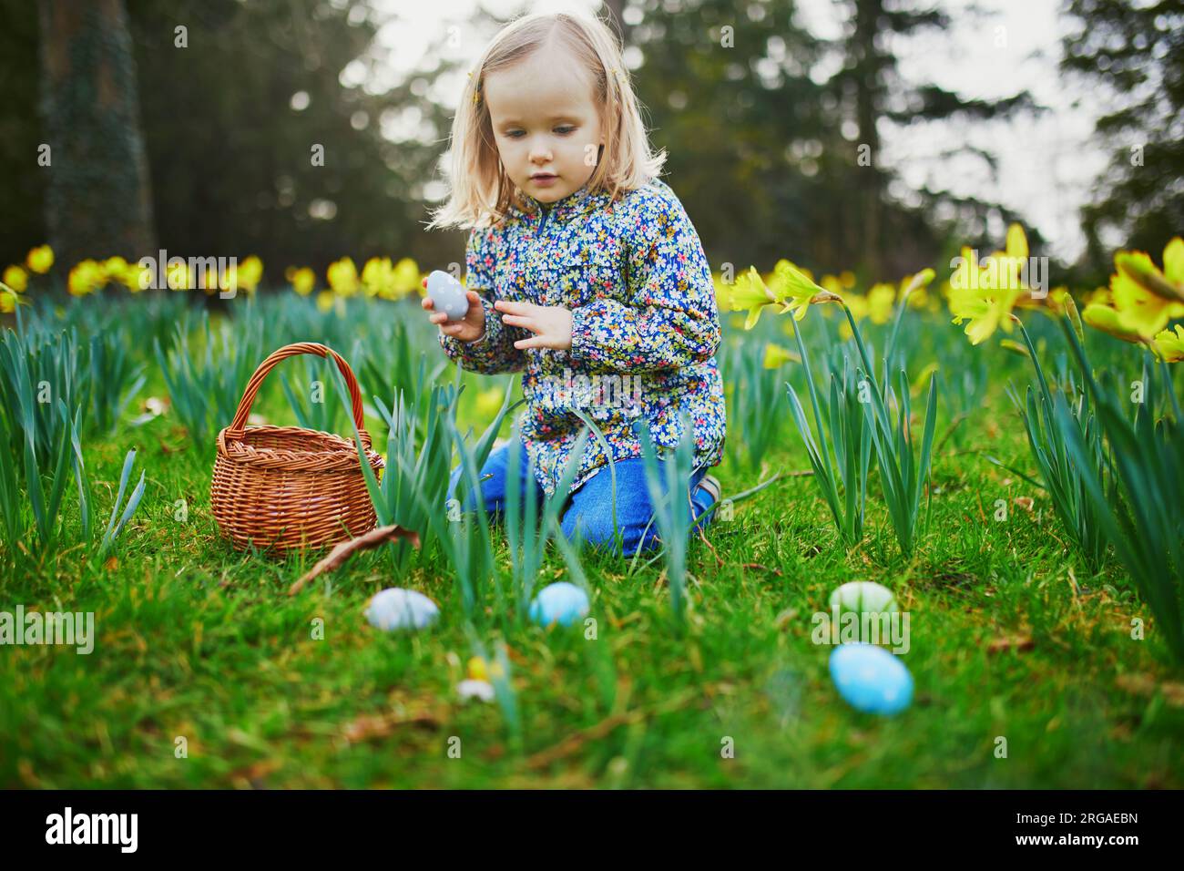 Three year old girl playing egg hunt on Easter. Child sitting on the ...