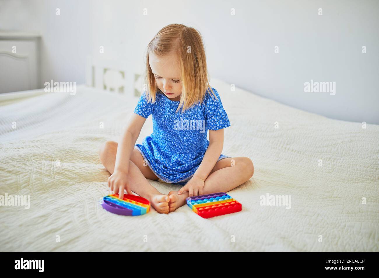 Adorable little girl playing with pop it fidget. Kid playing with ...