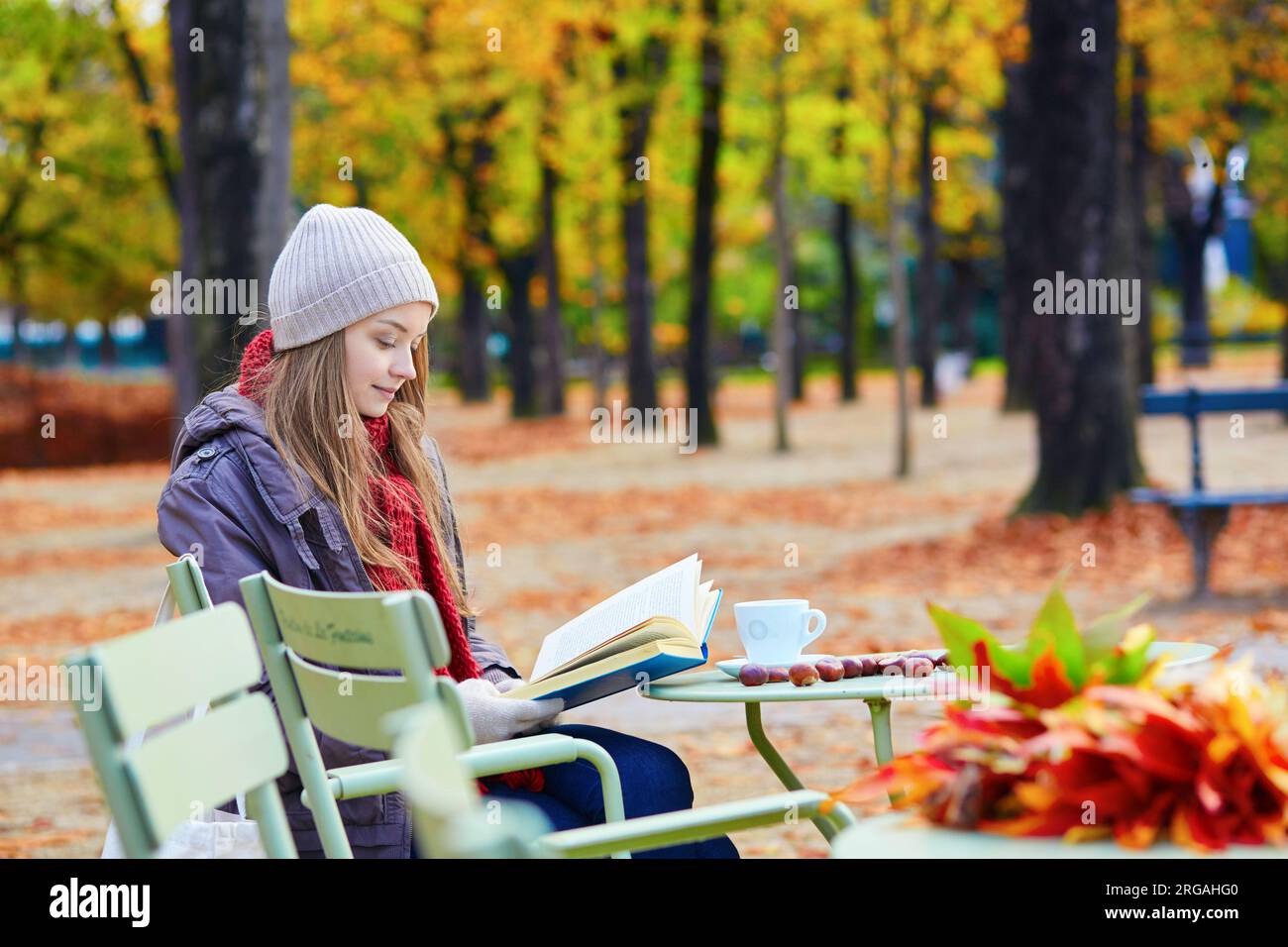 Girl reading a book in an outdoor cafe on a bright fall day in Paris ...