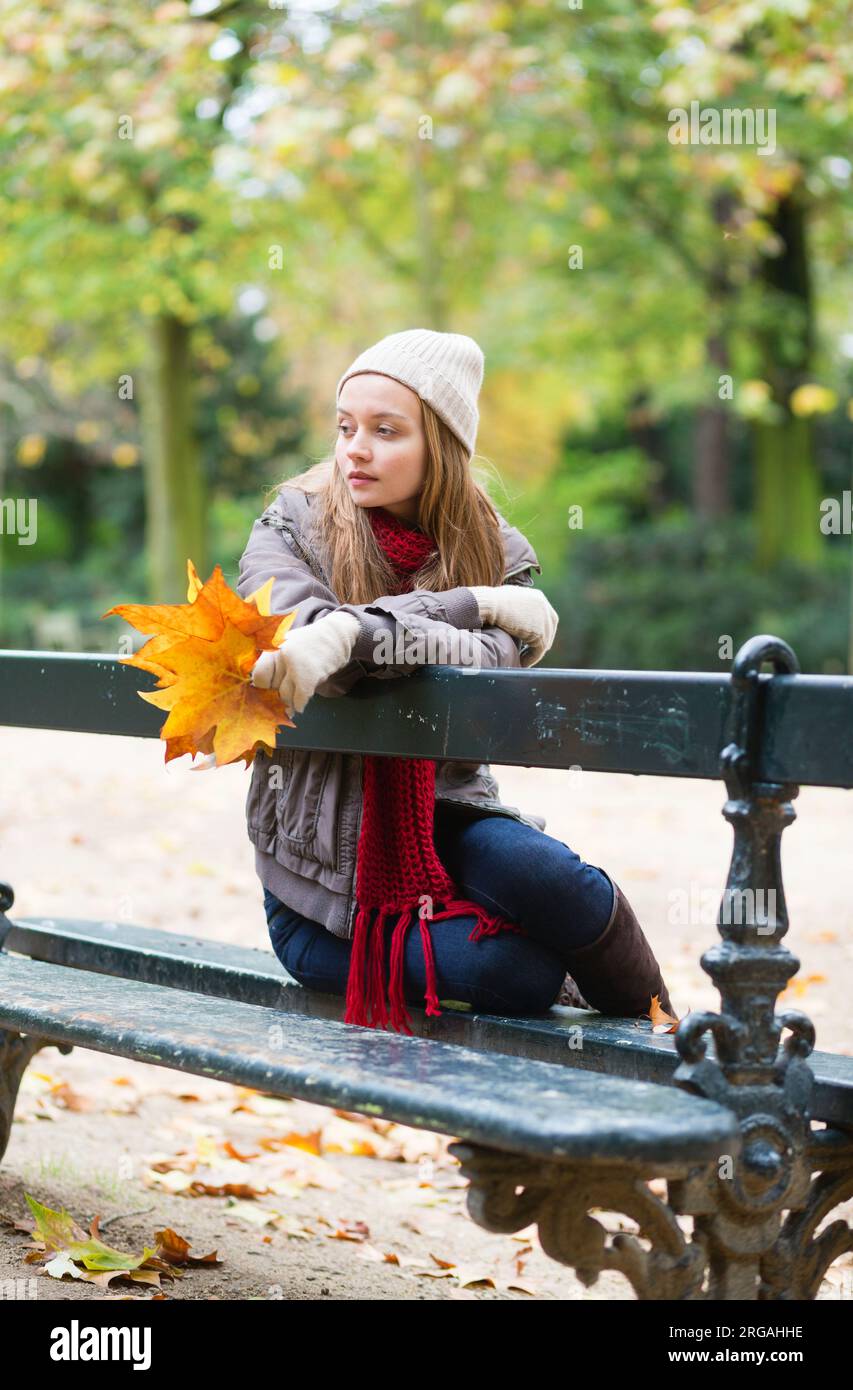 Sad girl sitting alone on the bench on a fall day Stock Photo - Alamy