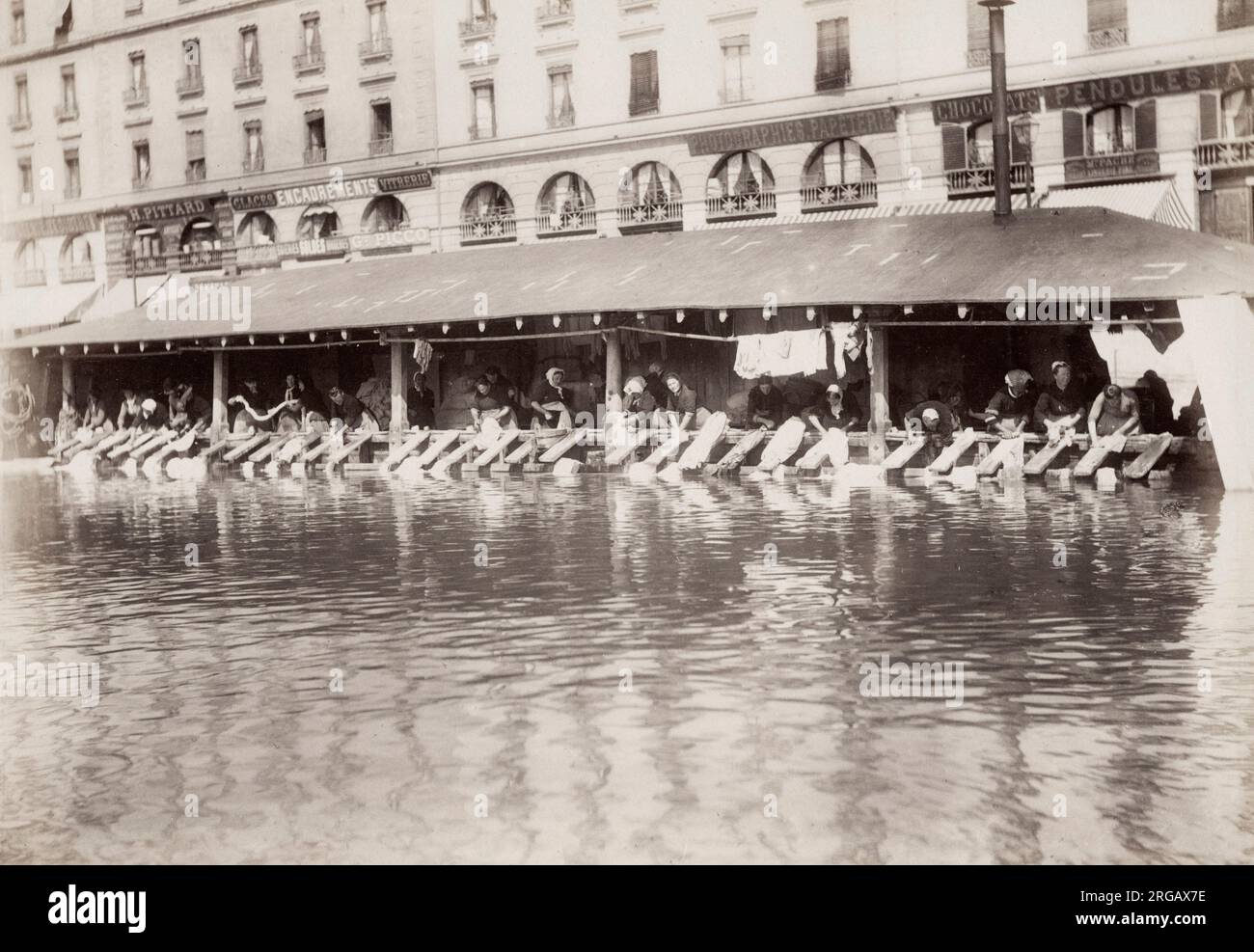 Vintage 19th century photograph: women washing clothes in a town river ...