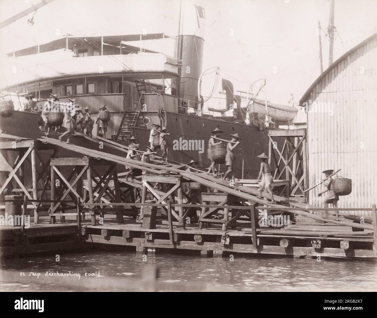 Vintage 19th century photograph: Ship discharging coal, porters ...