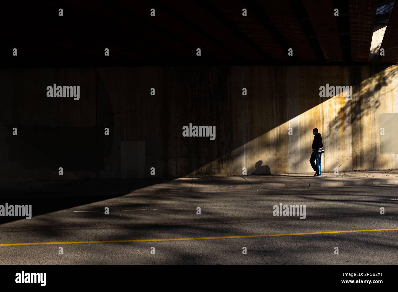 Man walking on side walk in tunnel with angled shadow in Toronto Canada ...